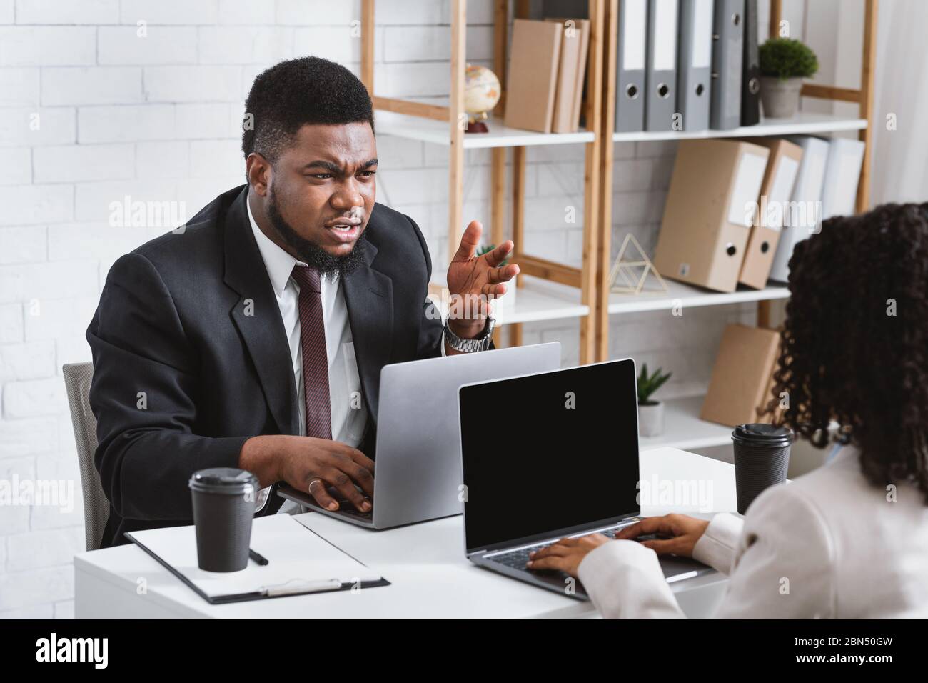 Young African American coworkers having argument at workplace, blank ...