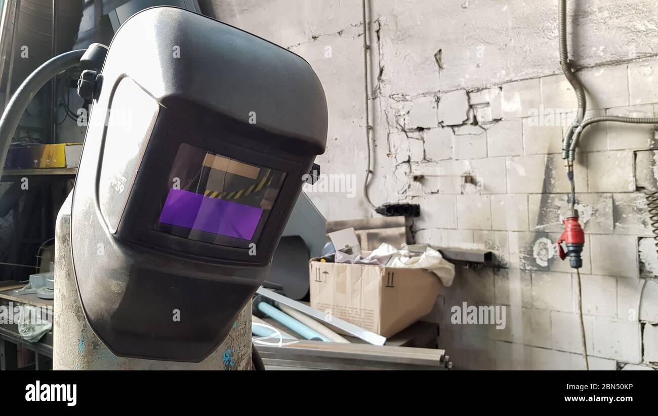 Messy old welding mask and equipment indoors with workshop background ...
