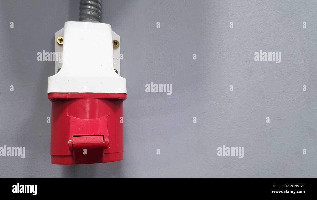 Three-phase 380 V high-voltage plug on a gray wall in a room with copy ...