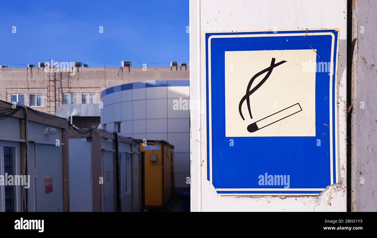 A blue square sign is pasted on the wall that explains the smoking area ...