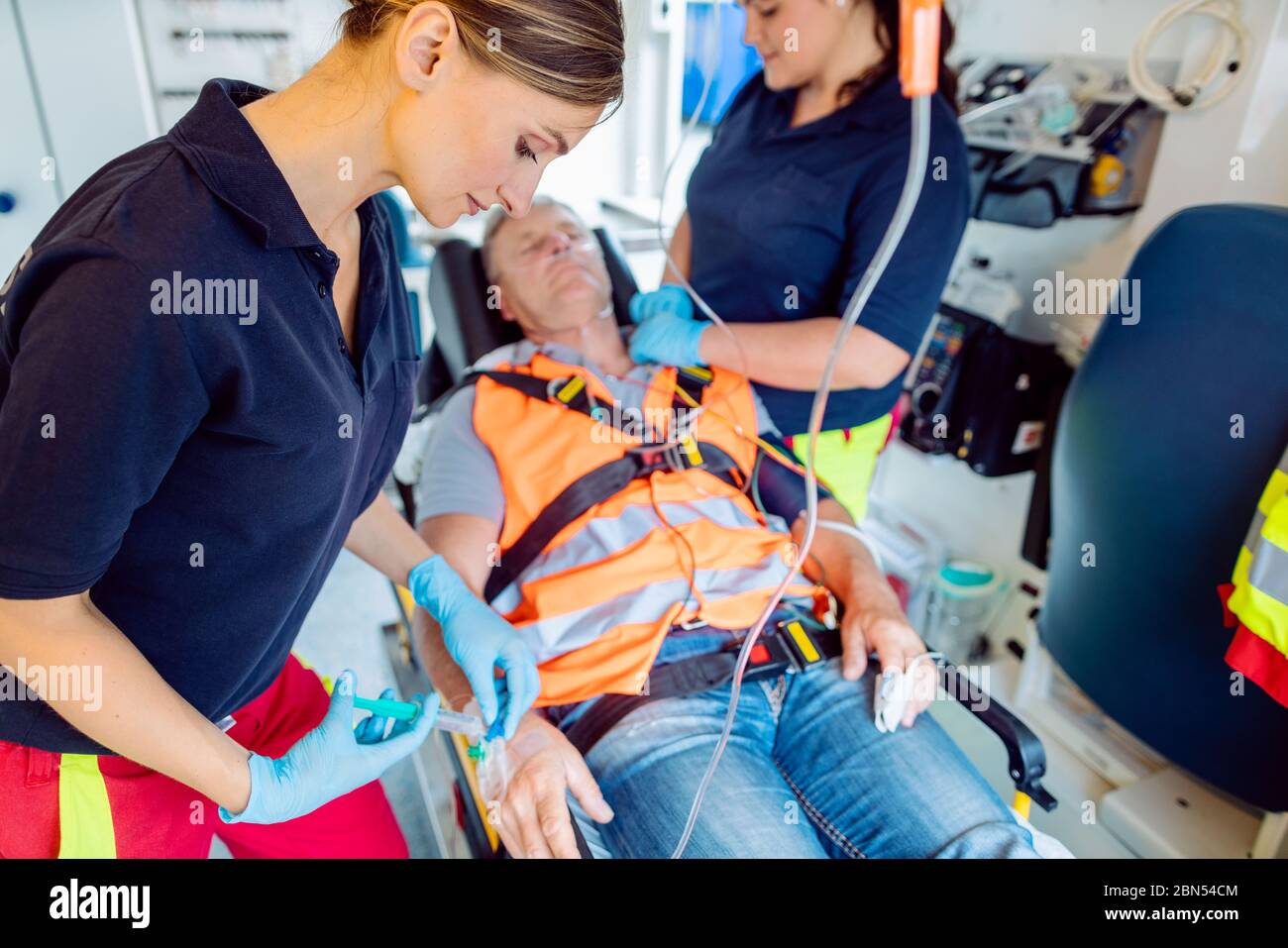 Emergency doctor giving drop injection to injured man in ambulance ...