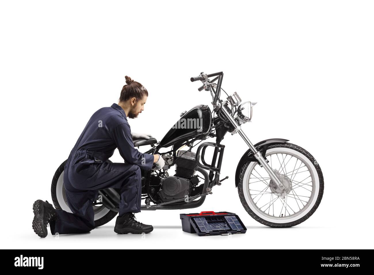 Motorcycle mechanic with a tool box repairing a chopper motorbike ...