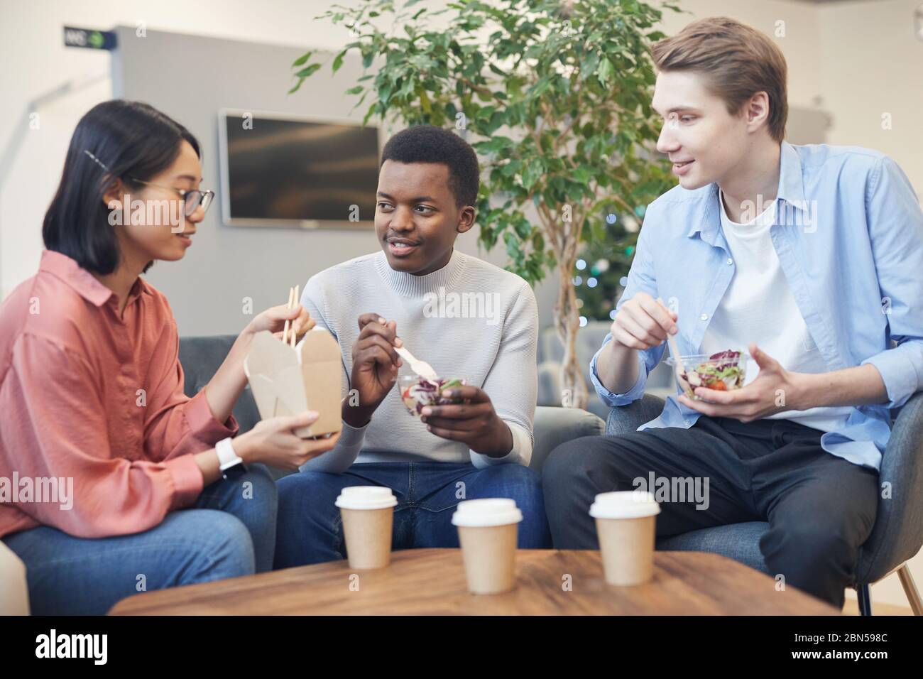 Multi Ethnic Group Of Young People Eating Takeout Food And Enjoying