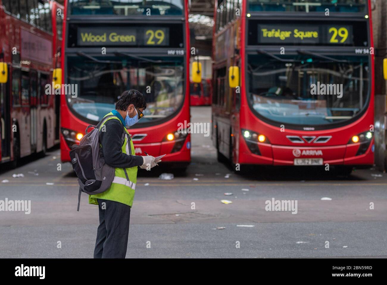 Asian bus supervisor wearing mask in bus garage, scheduling bus service ...