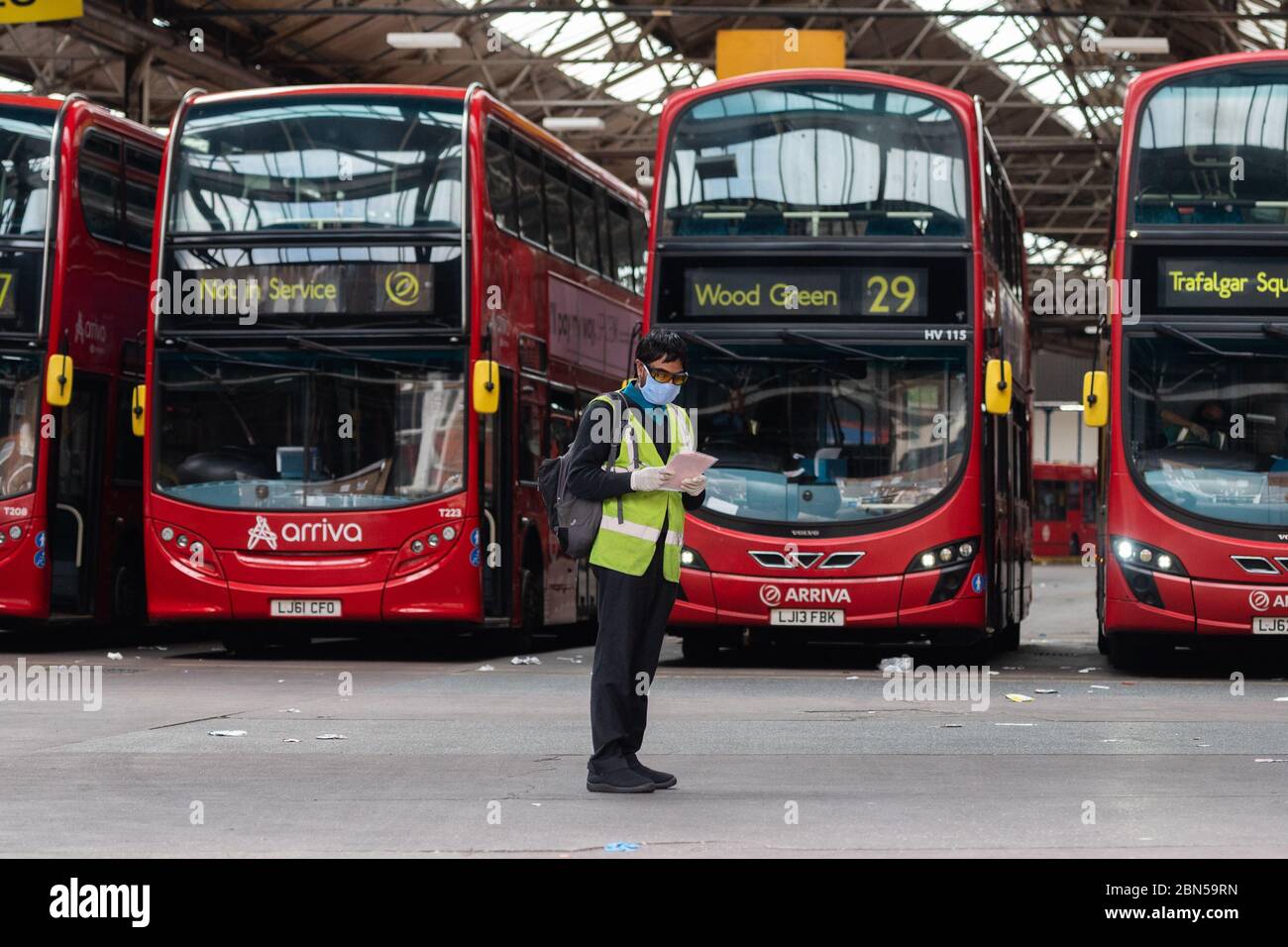 Asian bus supervisor wearing mask in bus garage, scheduling bus service ...