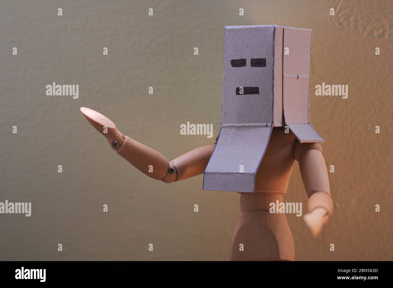 A dummy with a cardboard box with a painted face points one hand to the ...