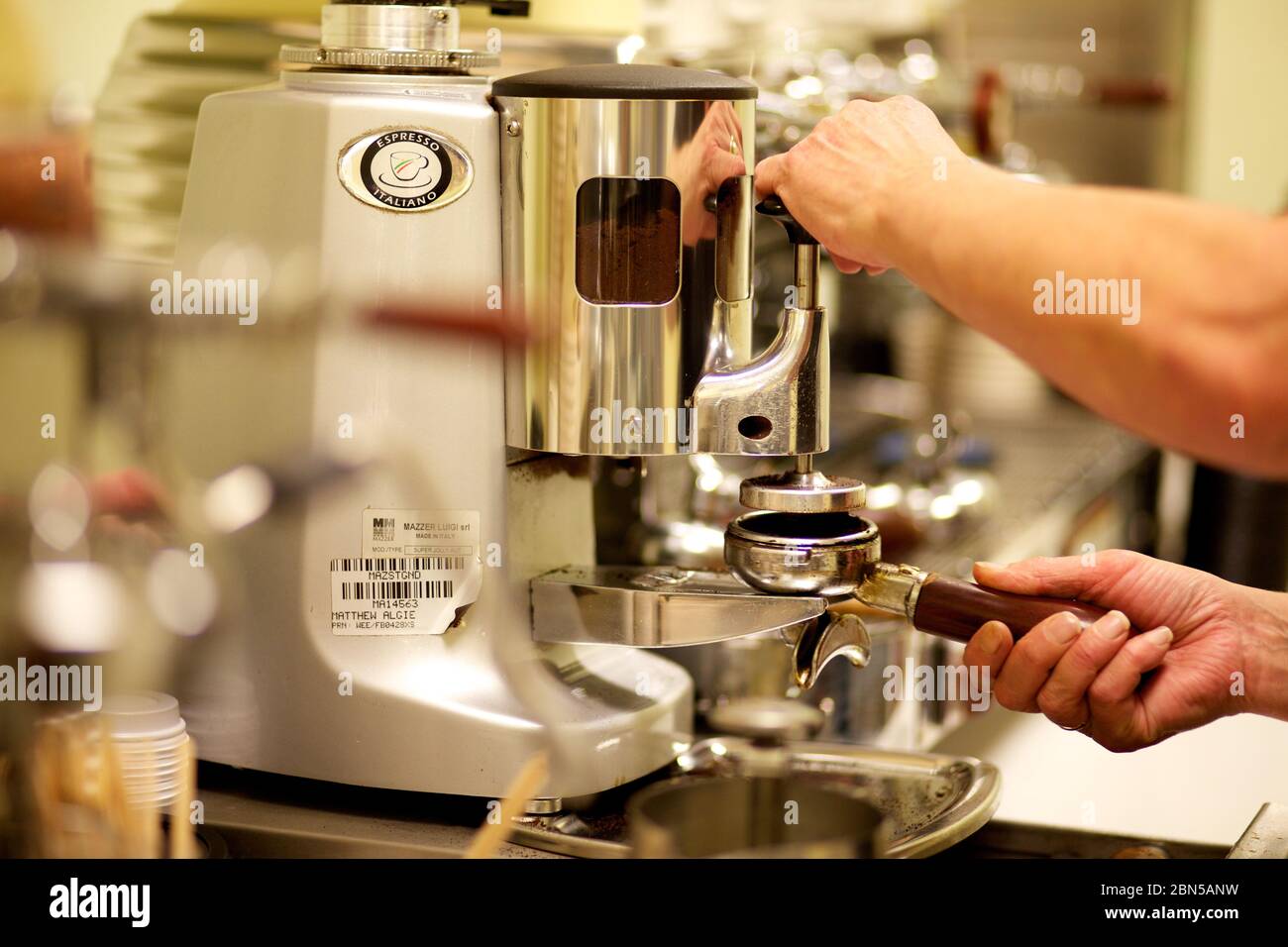 Coffee beans in a grinder being ground and pressed into the bucket of a ...