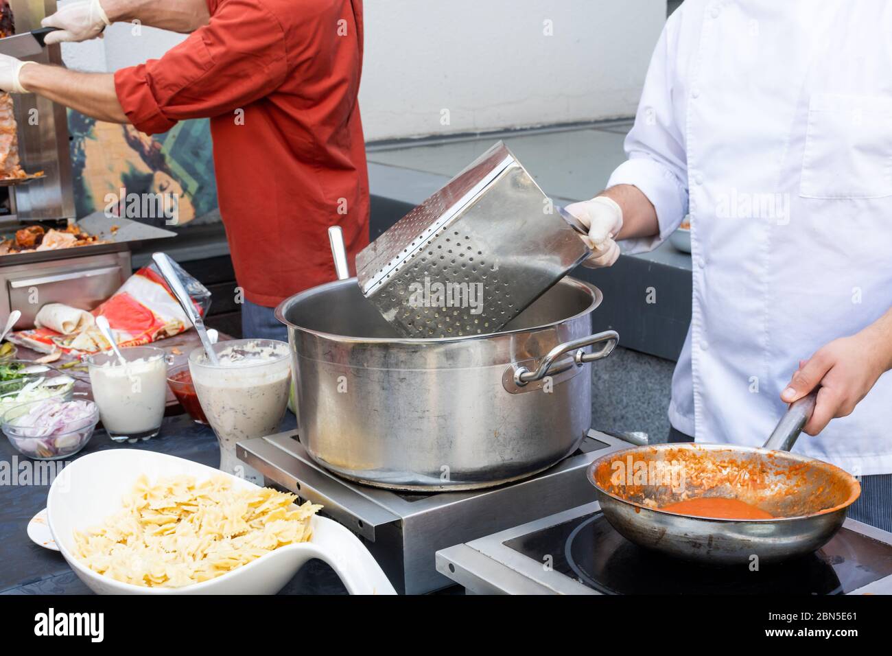 Chef preparing pasta boiling pasta and cooking. Food catering live ...