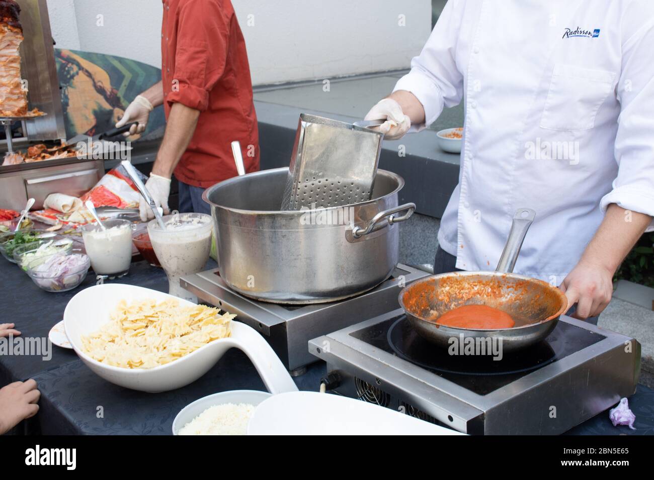 Chef preparing pasta boiling pasta and cooking. Food catering live ...