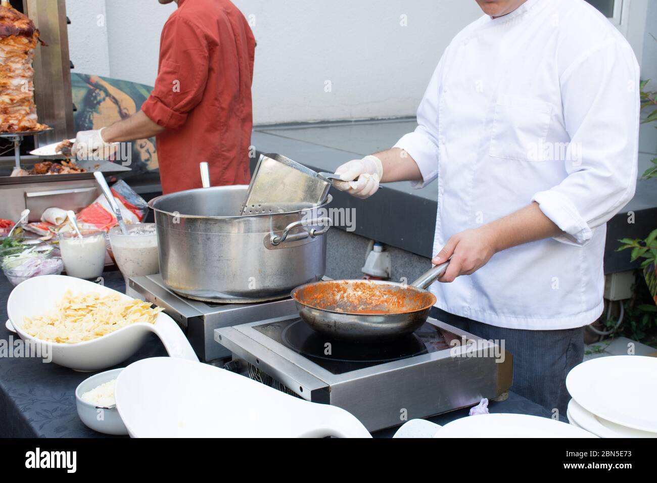 Chef preparing pasta boiling pasta and cooking. Food catering live ...