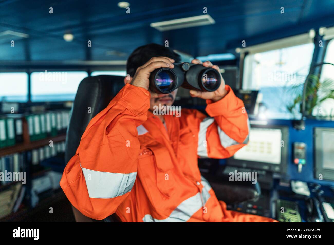 Filipino deck Officer on bridge of vessel or ship looking through ...