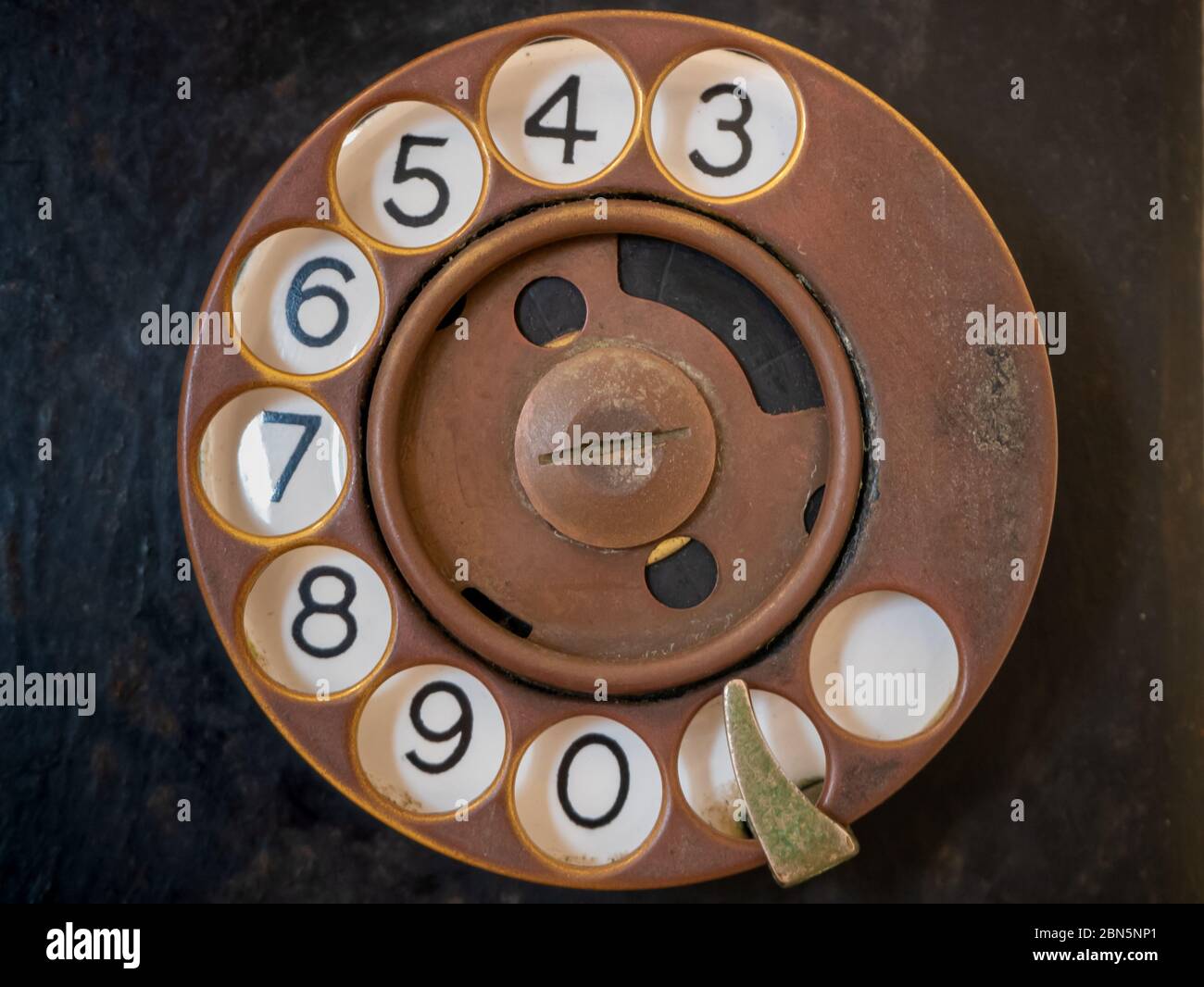 Antique telephone rotary dial with numbers and tarnished metal finish ...