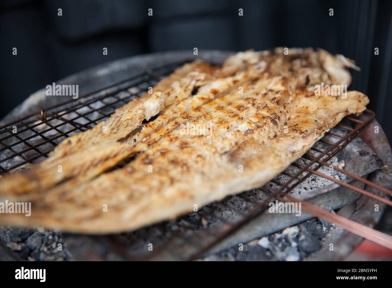Korean traditional Fish being grilled on a charcoal fire on a small ...
