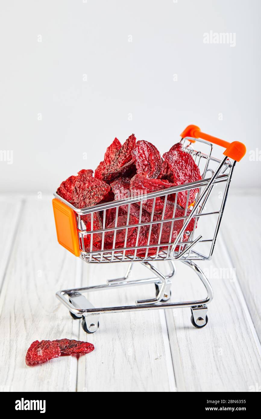 Diet healthy eating concept. Dried beet chips in a toy grocery cart on ...