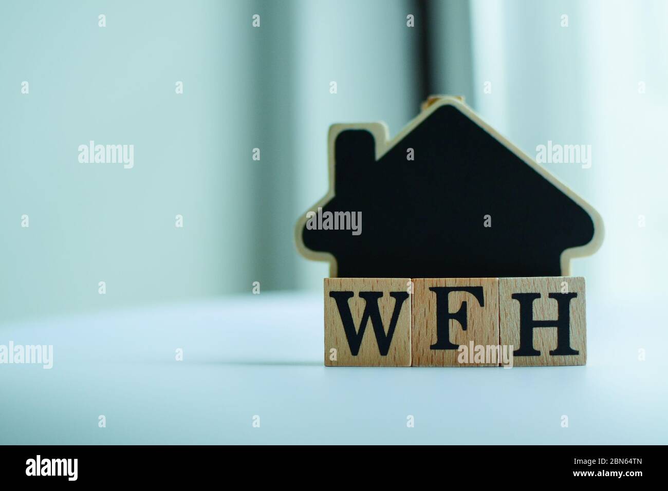 WFH wooden block (stand for working from home) with house model. People ...