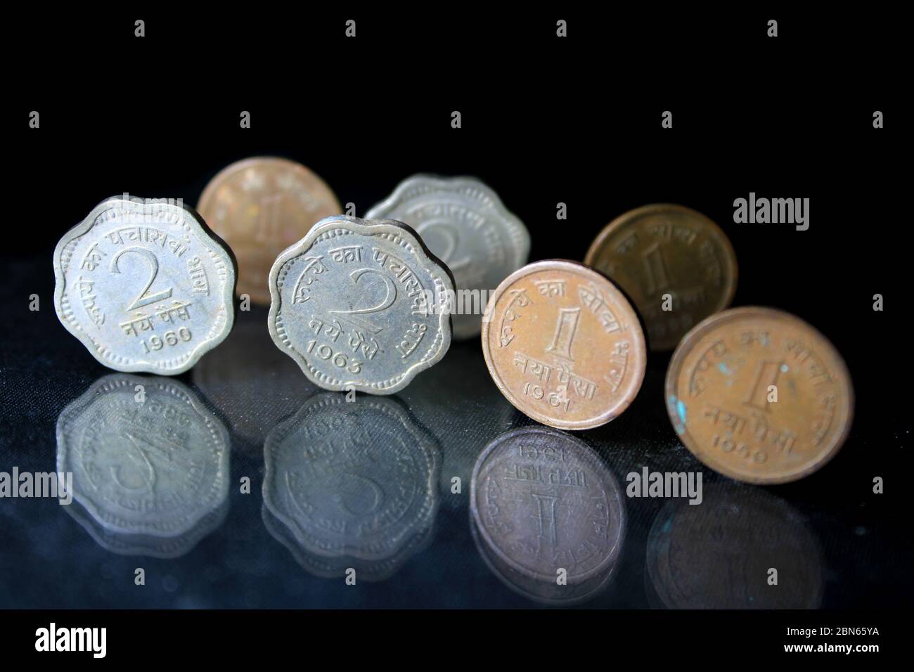 An old vintage Indian one paisa and two paisa coins isolated on a black ...