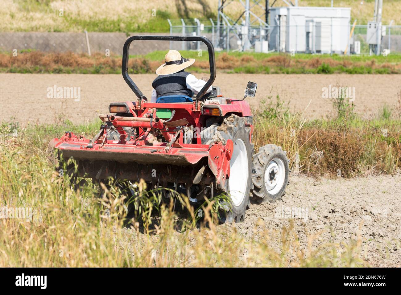 Red tractor plowing the rice field farmland Stock Photo - Alamy