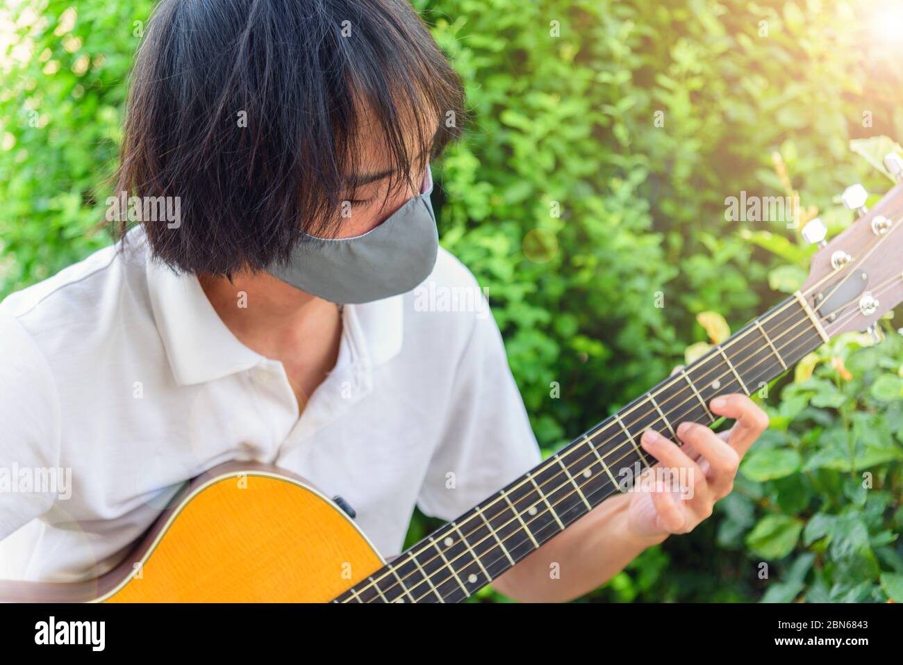 The man wear mask and playing guitar in the park / wear mask and ...