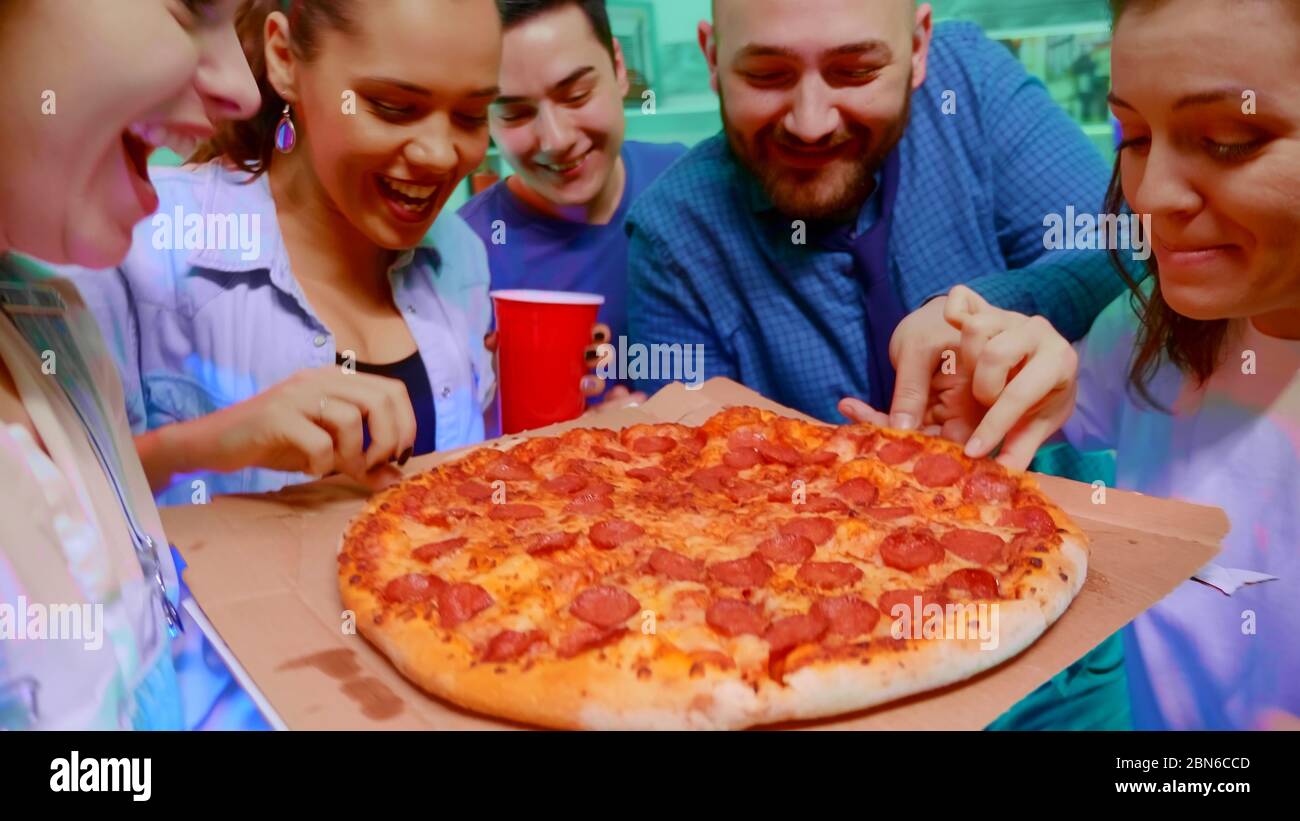 Follow shot of girl arriving at the party with delicious pizza for her ...