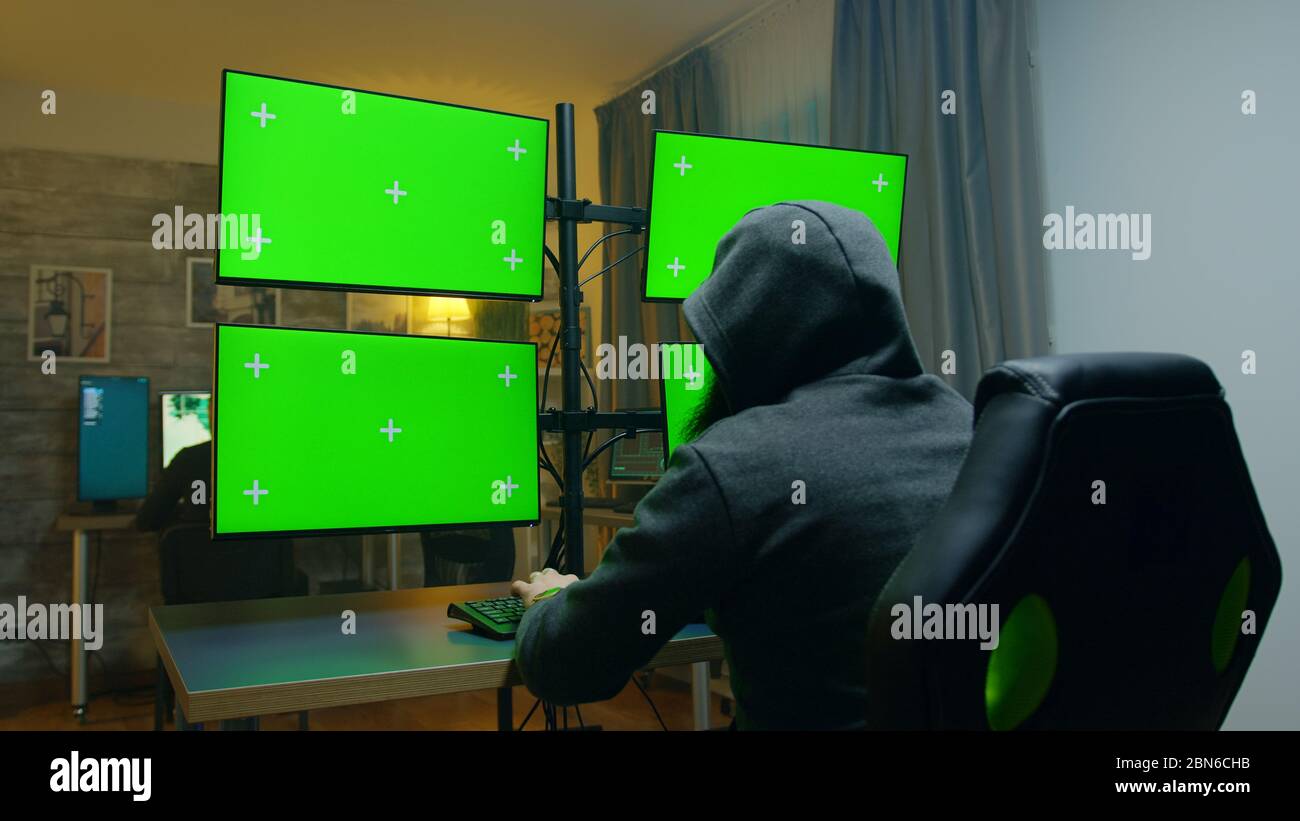 Bearded hacker hiding his face wearing a hoodie using computer with ...