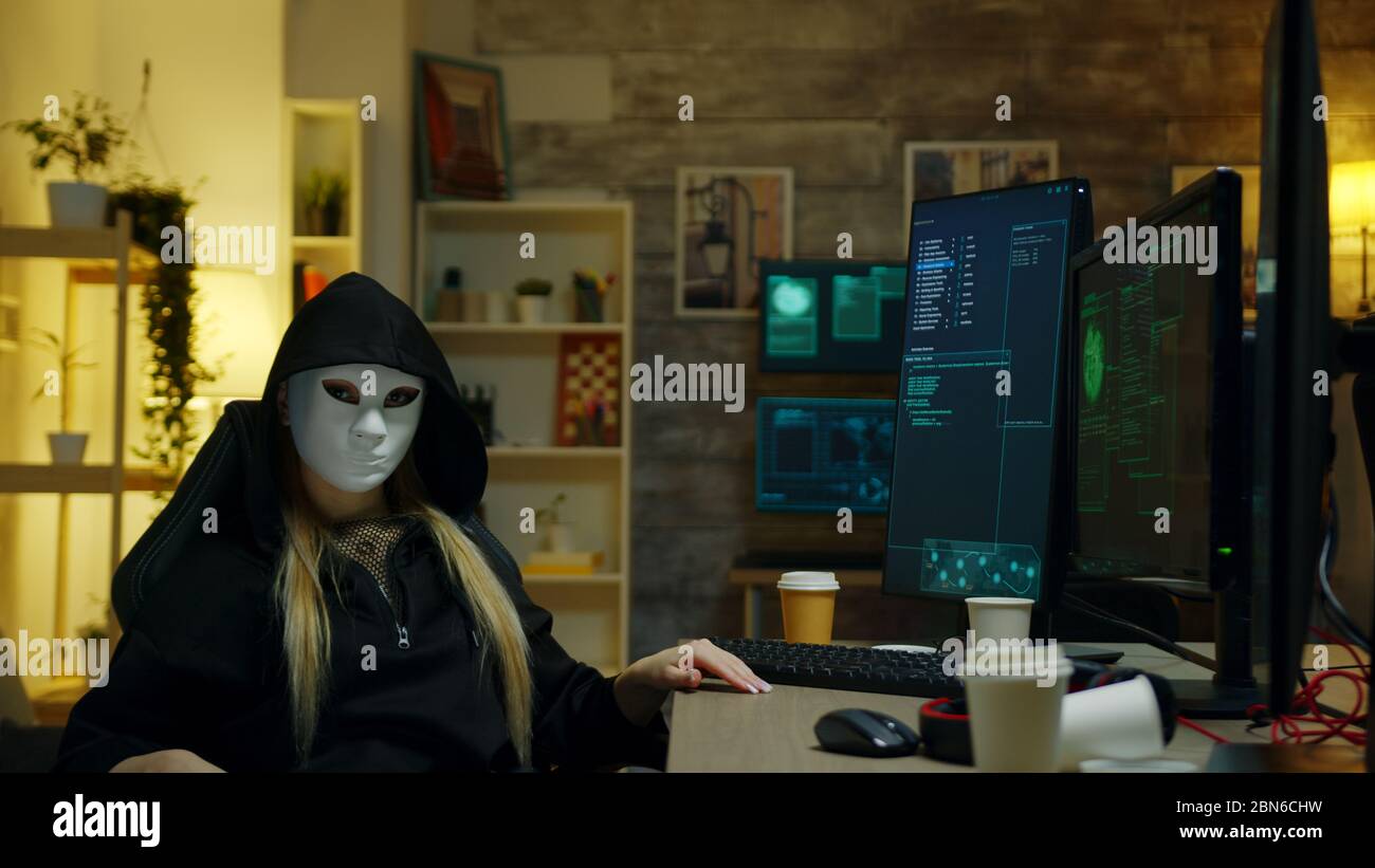 Hacker girl wearing a white mask to hide her identity. Looking into the ...