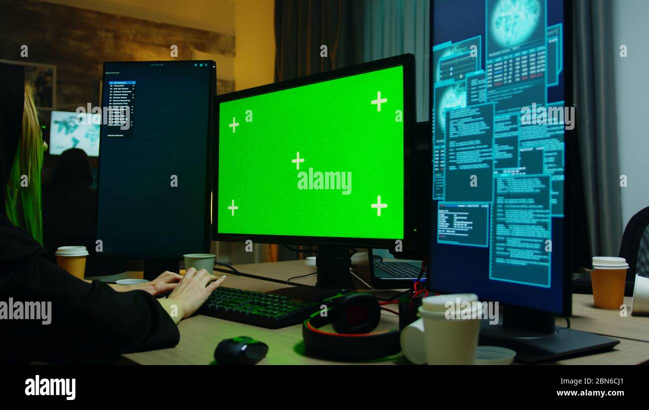 Zoom in shot of hacker girl in front of computer with green screen ...