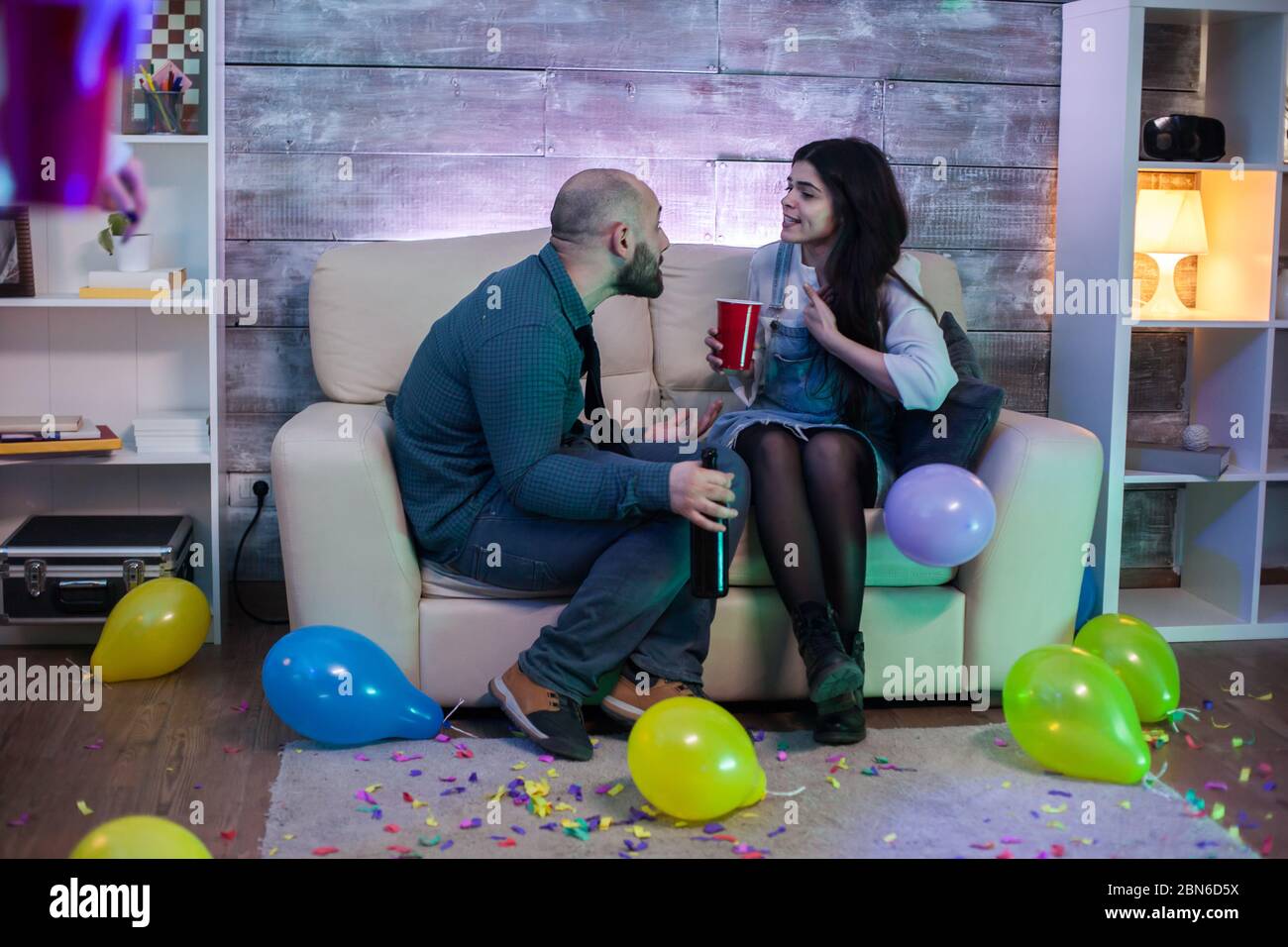 Young couple having an argument sitting on the couch at their friends ...