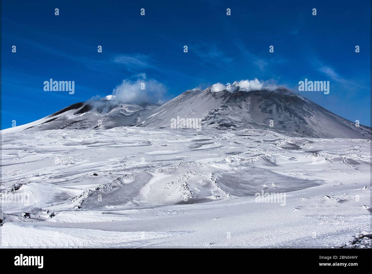 Snowy volcano with smoke in sicily with blue skies Stock Photo - Alamy