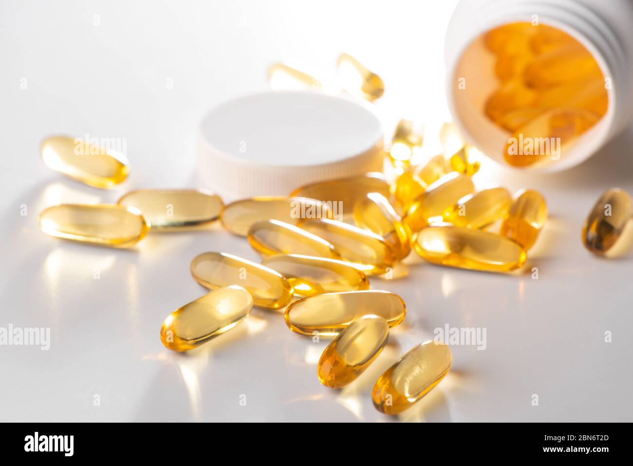Yellow capsules scattered from a bottle on white background Stock Photo ...