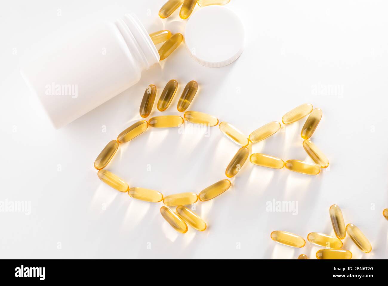Fish shape made of yellow capsules and bottle on white background Stock ...