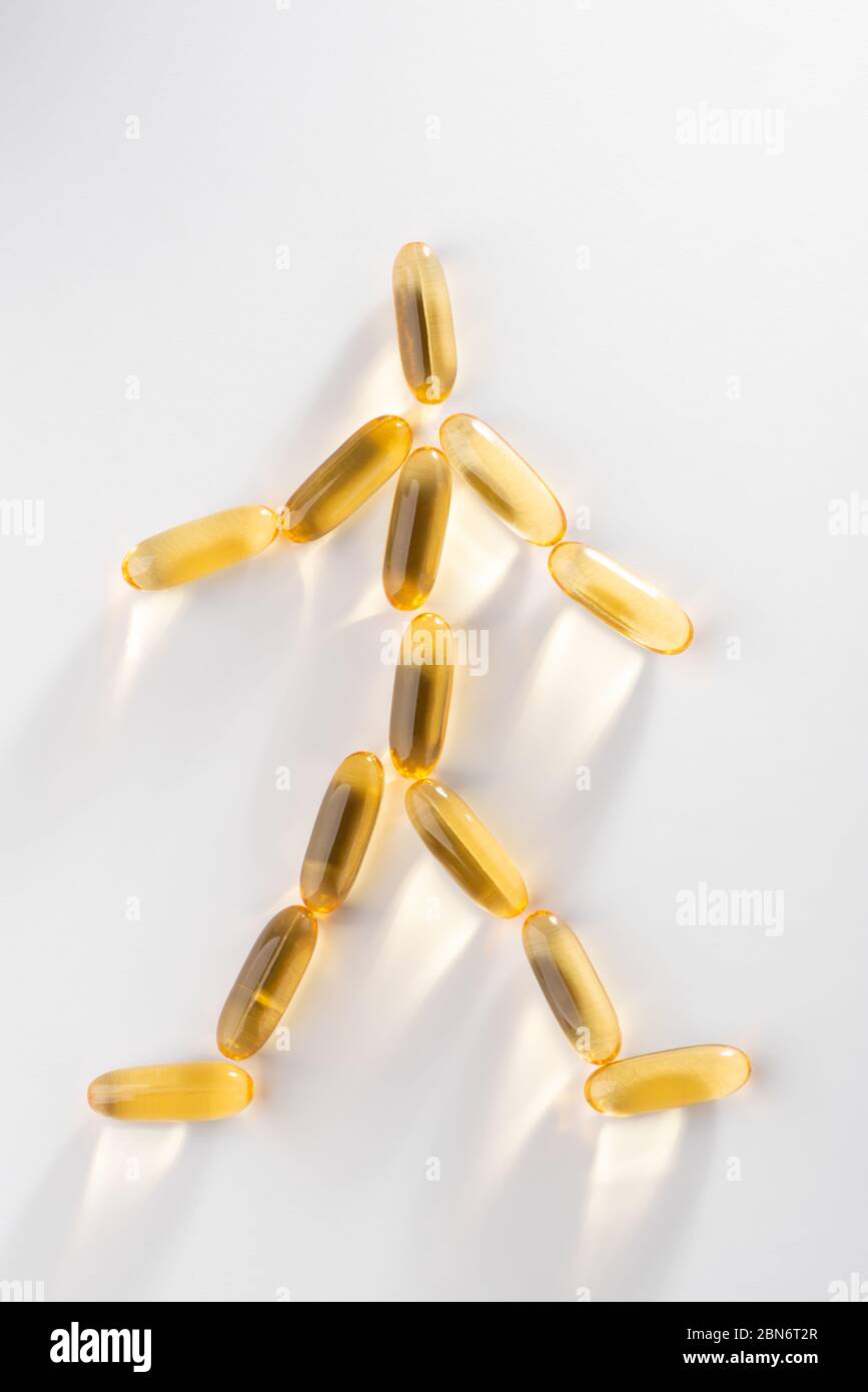 Man figure layed out with omega 3 capsules Stock Photo - Alamy