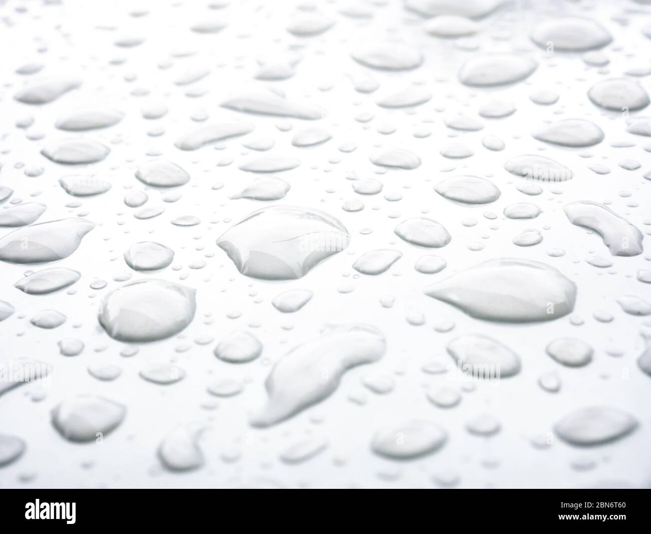 Transparent drops of water on a white glossy surface. Abstract ...