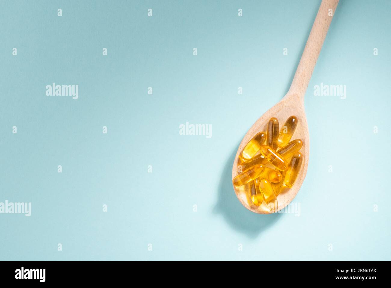 Wooden spoon of Omega-3 capsules on blue background Stock Photo - Alamy