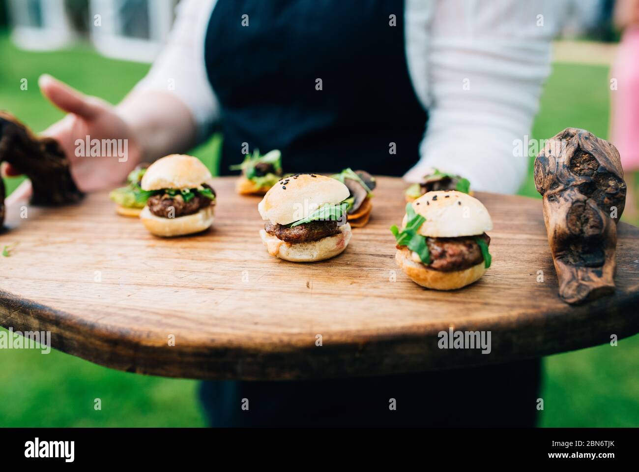 a waitress holding a wooden board serving canapes outside at a british ...
