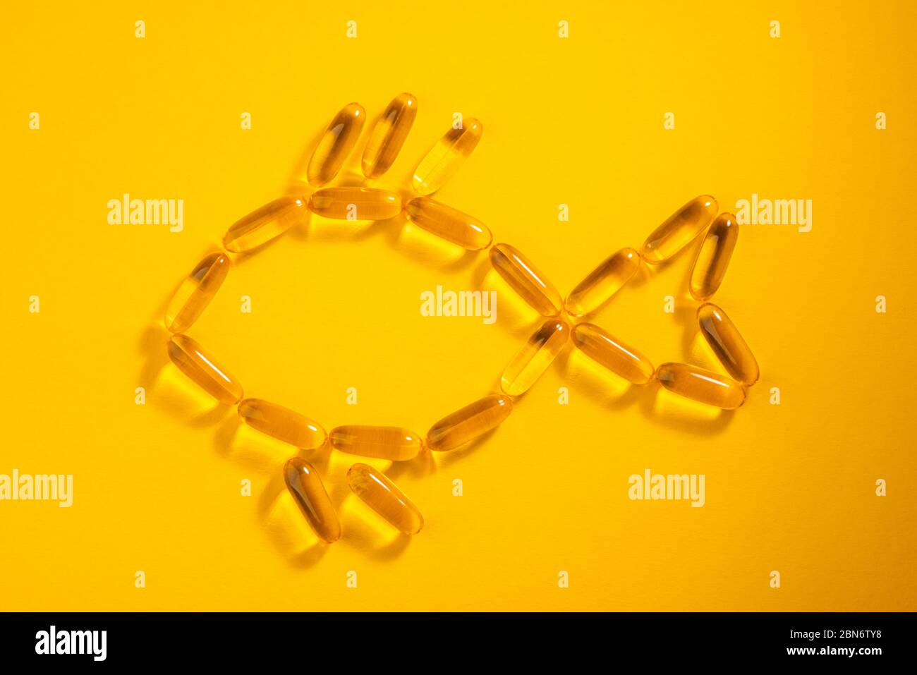 Fish shape made of cod liver oil capsules on orange background Stock ...