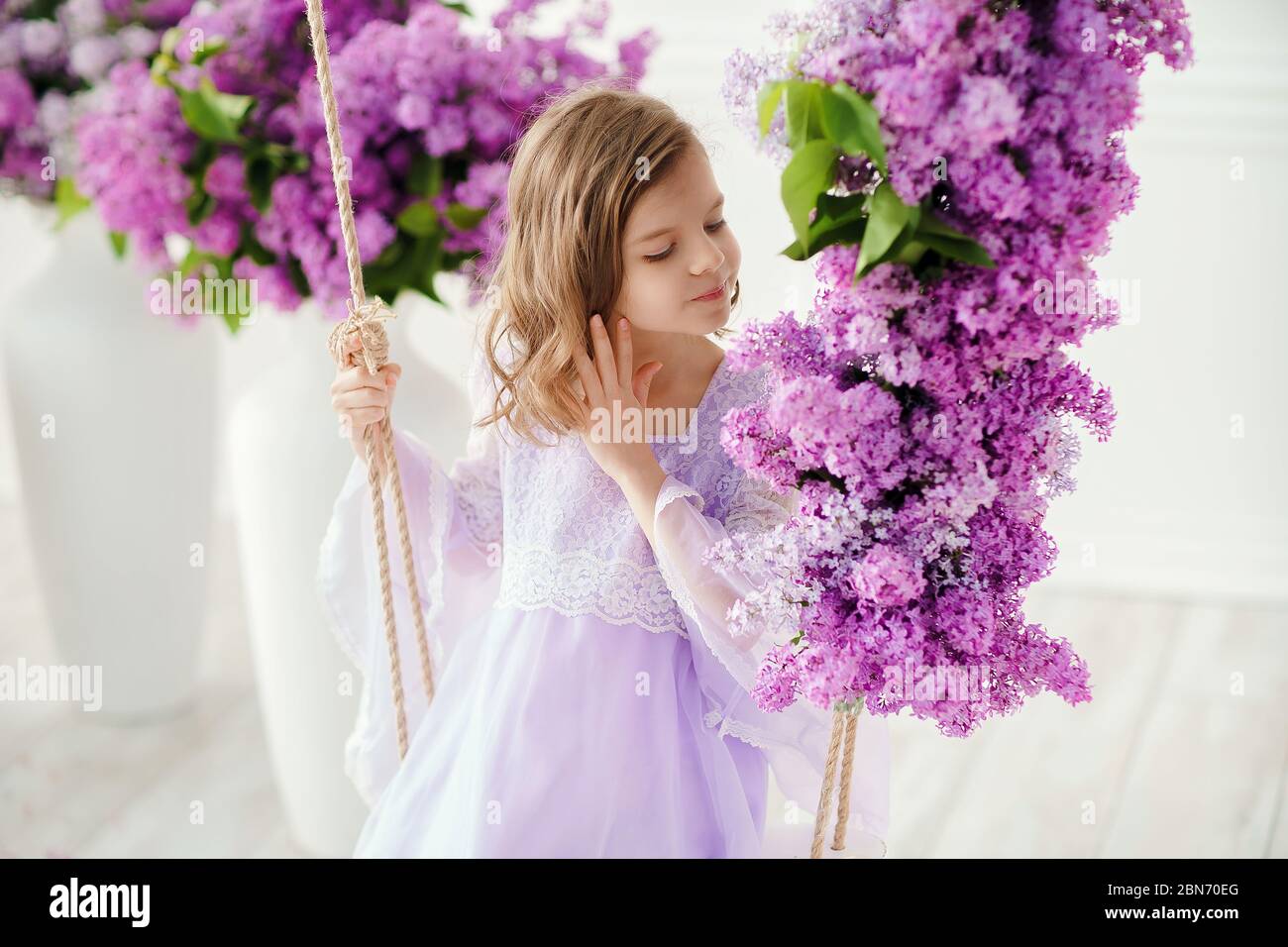 Beautiful little girl of preschool age in a delicate dress sitting on a ...