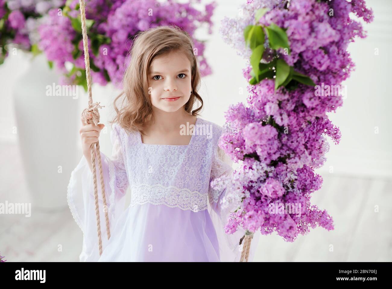 Beautiful little girl of preschool age in a delicate dress sitting on a ...