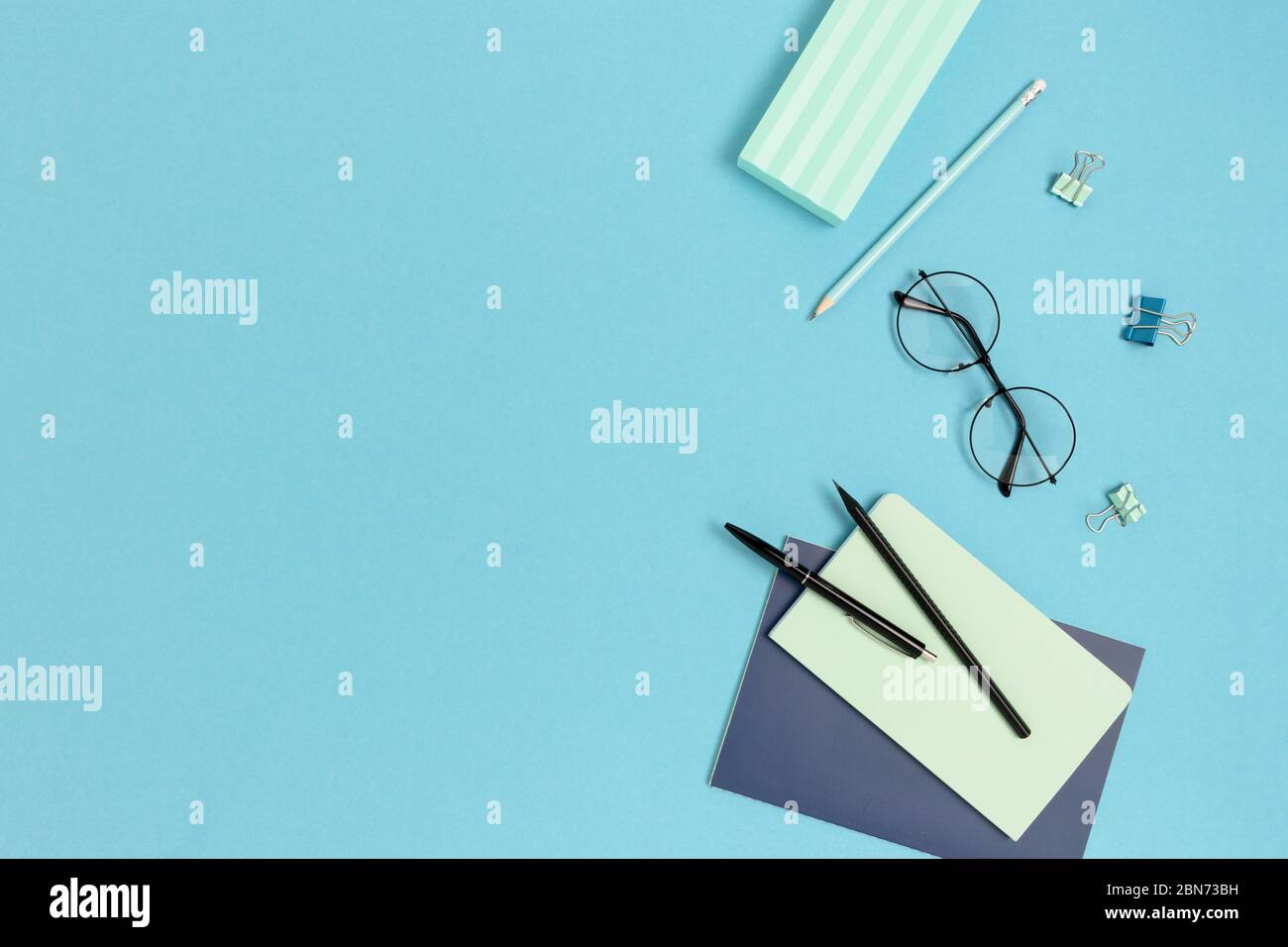 Top view of glasses, stationery and copybooks on a blue pastel ...