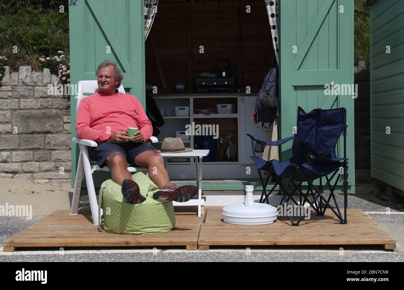 Rob Underhill looks out to sea as he sits outside his beach hut on ...