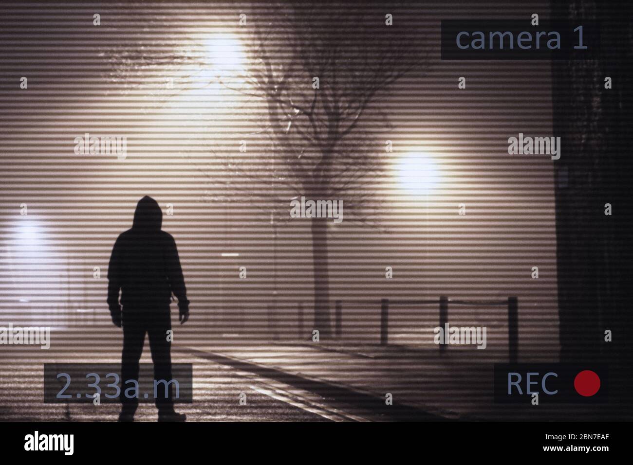 A scary hooded figure standing next to street lights on a foggy winters ...