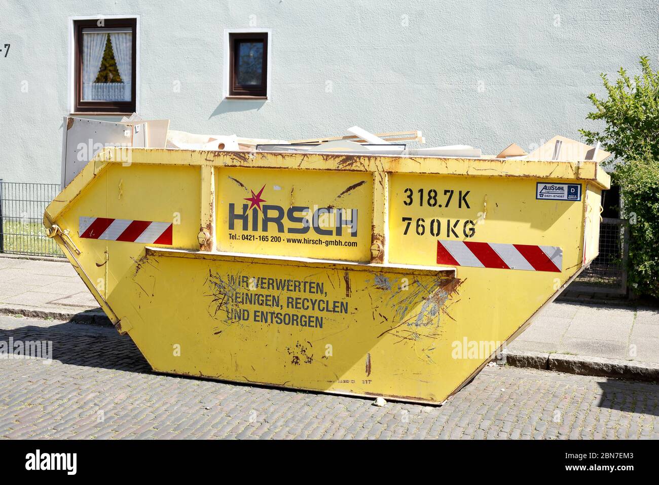 Yellow skip for building rubble standing on the street in front of a ...