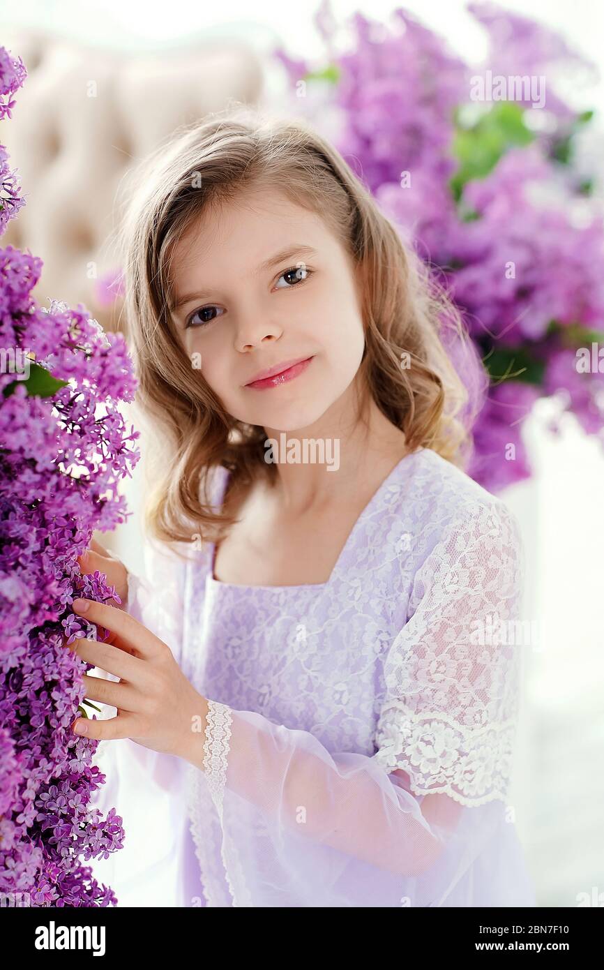 Beautiful little girl of preschool age in a delicate dress sitting on a ...