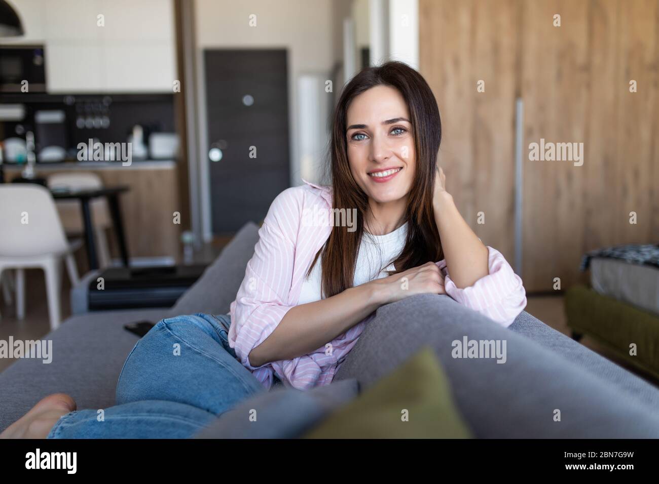 Happy young woman lying on couch and relaxing at home, casual style ...
