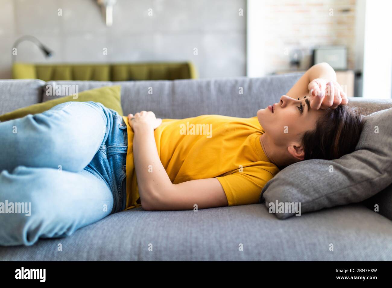 Sick woman lying on sofa in the living room with stomahc ache Stock ...