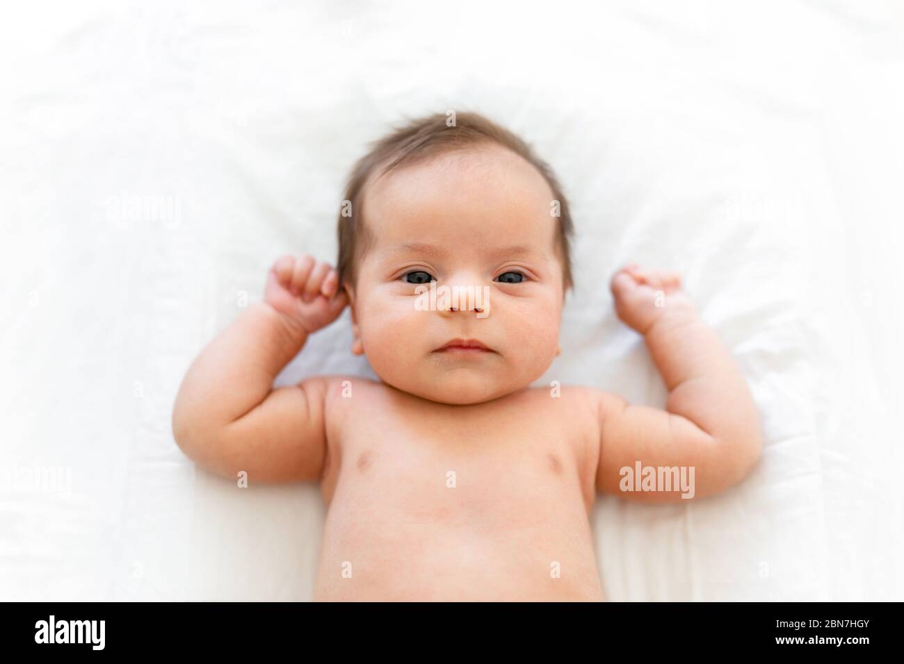 Adorable beautiful newborn baby cradled in its mothers hands looking up ...