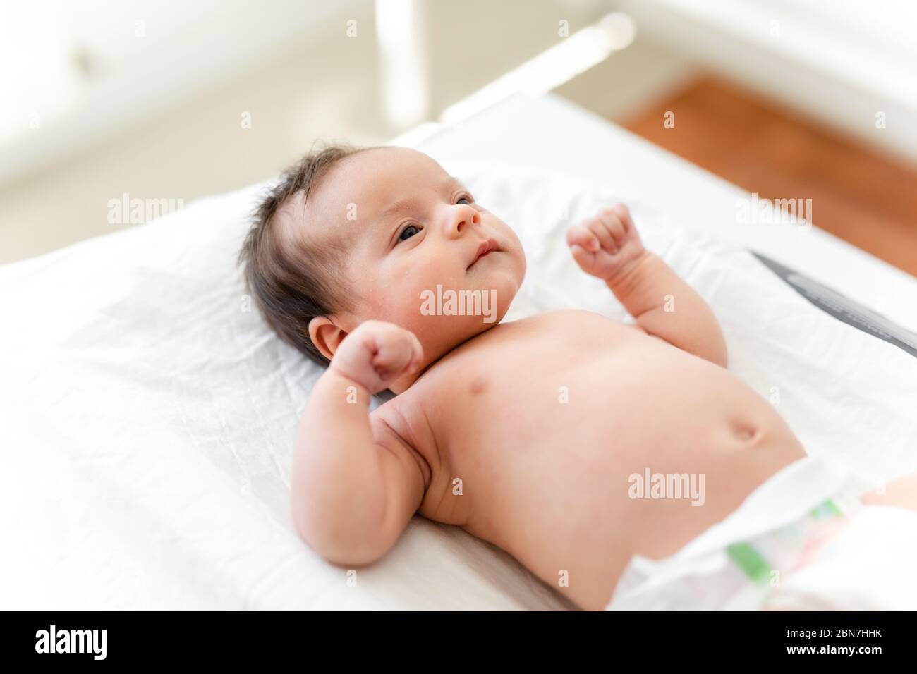Adorable beautiful newborn baby cradled in its mothers hands looking up ...