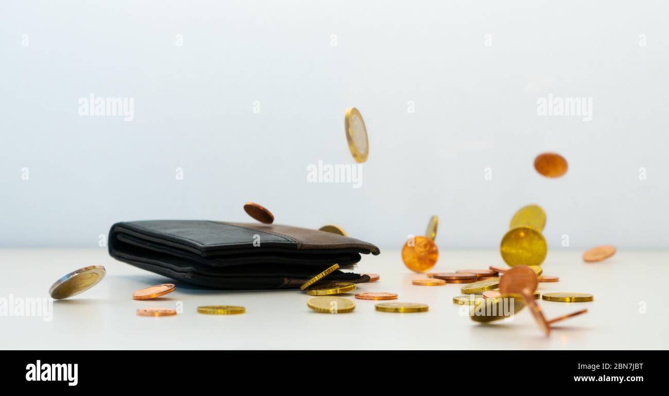heaps of coins falling over wallet Stock Photo - Alamy