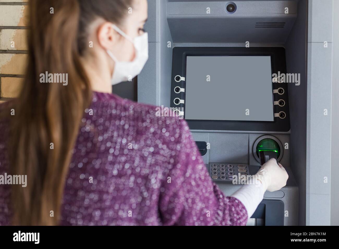 Rear view of young woman wearing protective surgical face mask and ...