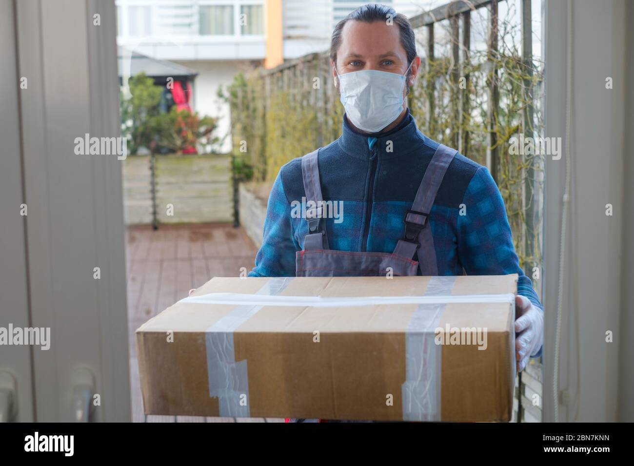 Courier protected with mask and gloves delivering parcel to a customer ...