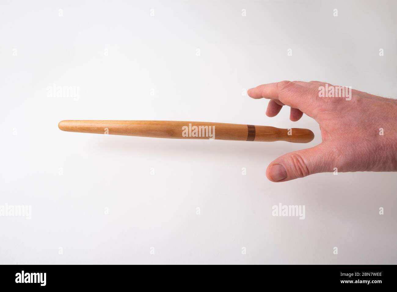 A male hand reaches fof a handmade spirtle made from cherry and walnut ...